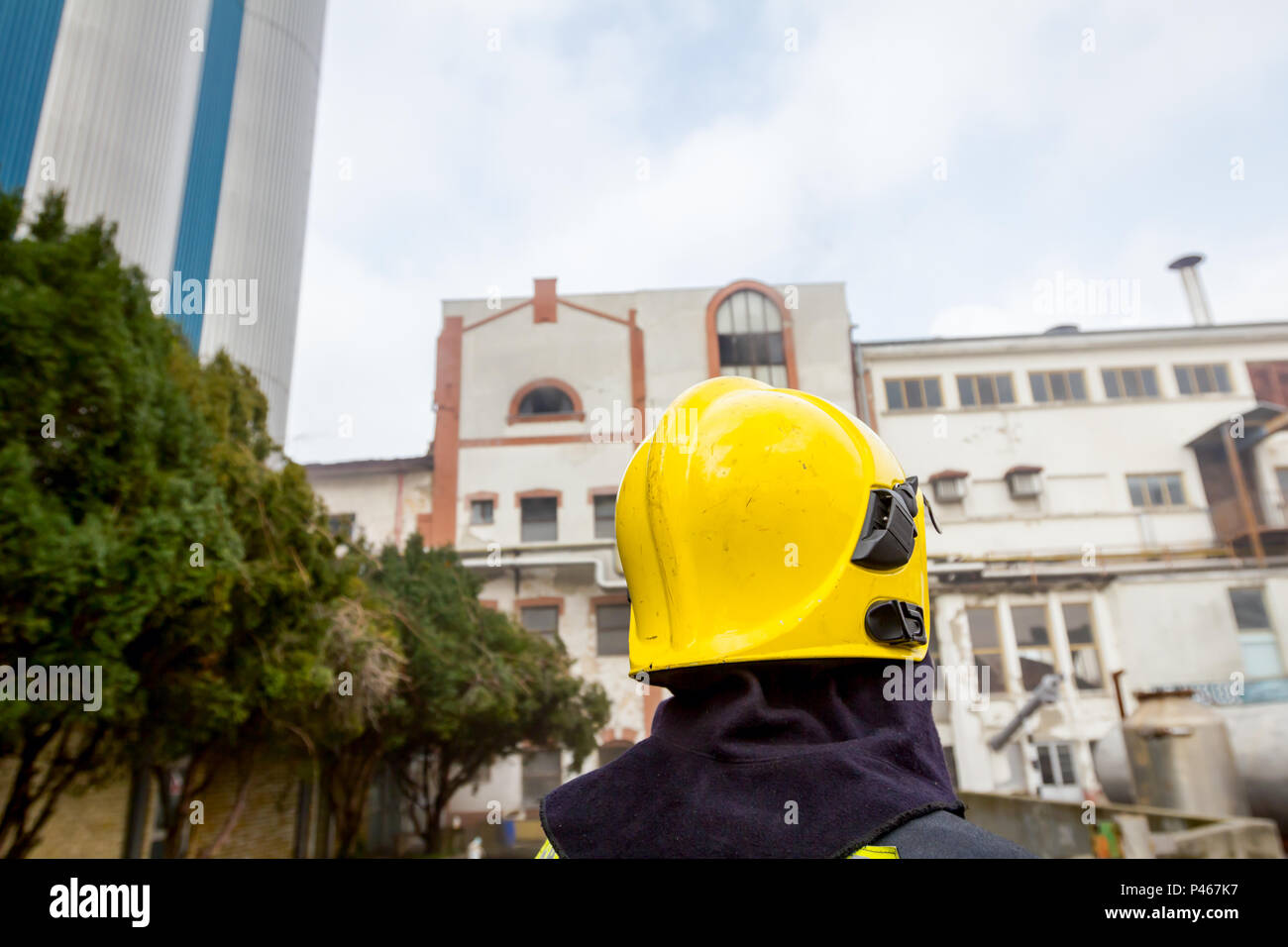 View from behind on firefighter with safety yellow helmet. Fireman is ...