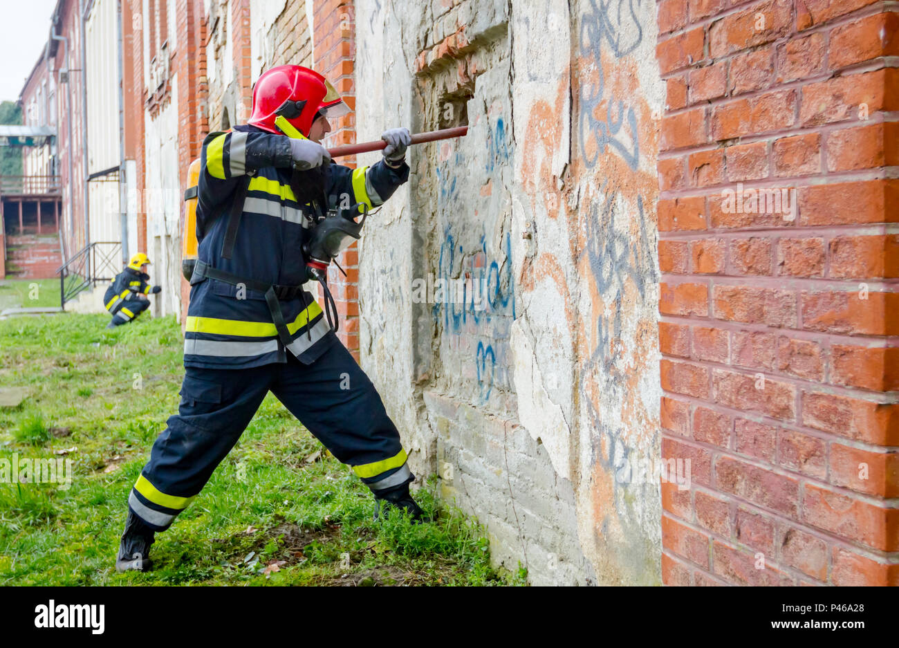 View from behind on firefighter in uniform with full safety gear, using ...