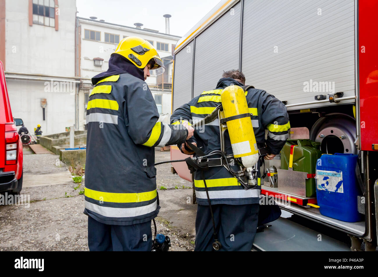 Firefighter is helping fellow to assembly his gear, keep balance and ...