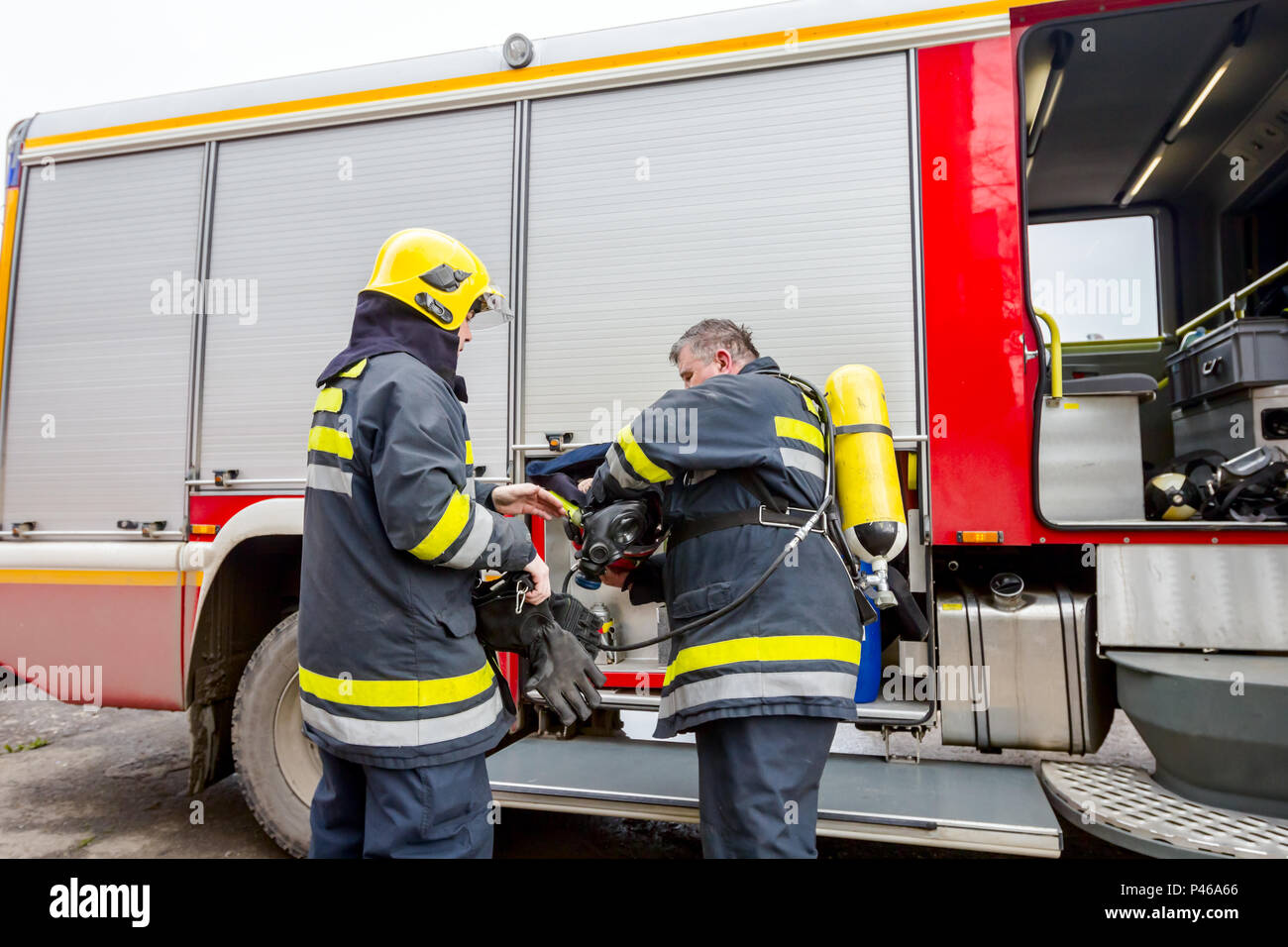 Firefighter is helping fellow to assembly his gear, keep balance and ...