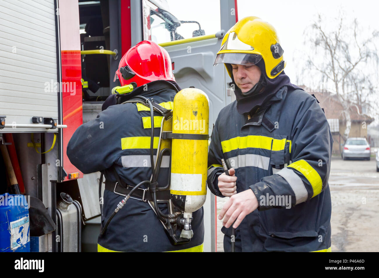 Firefighter is helping fellow to assembly his gear, keep balance and ...