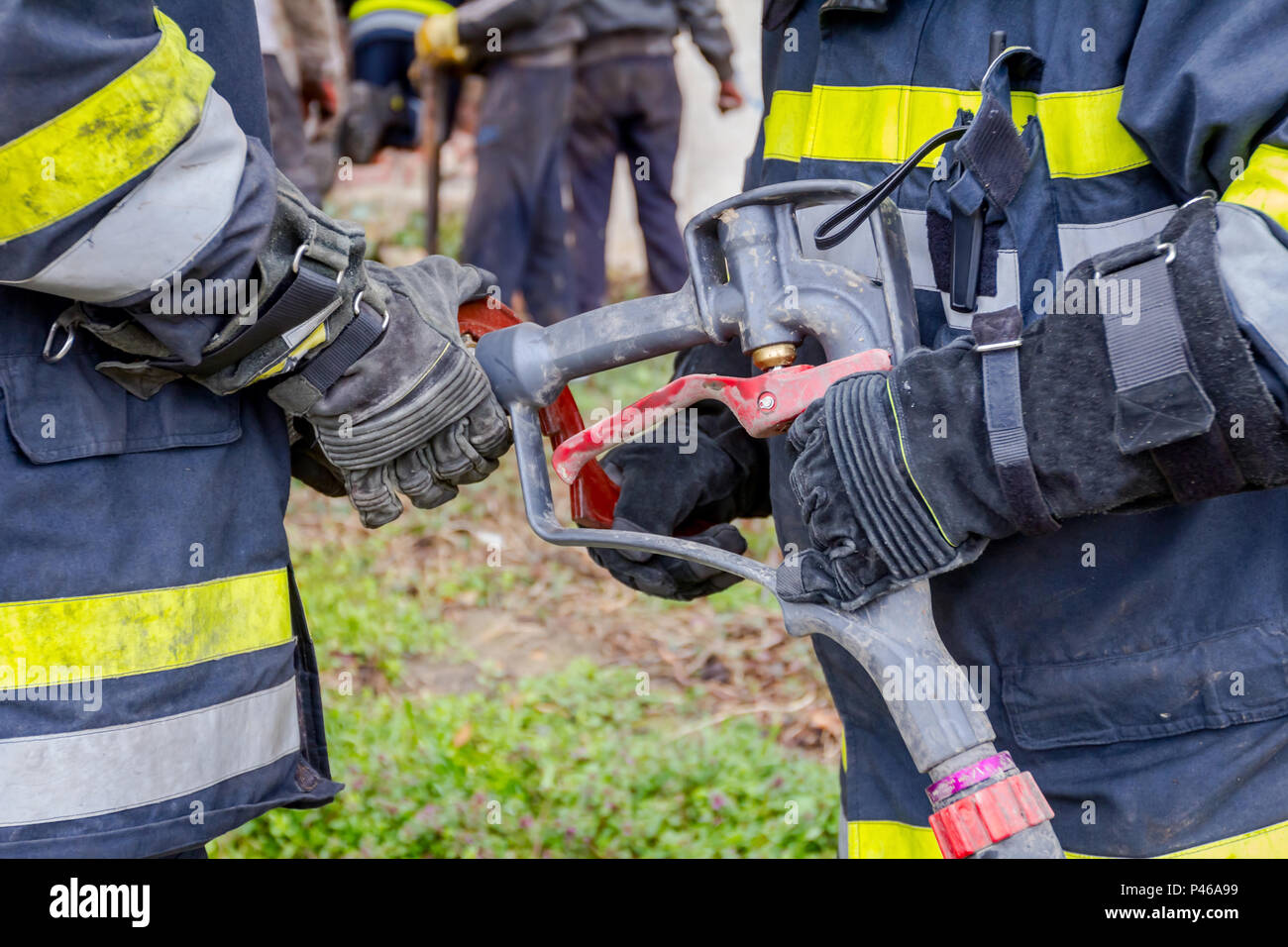 Firefighter is helping fellow to assembly water gun on the hose coupler ...