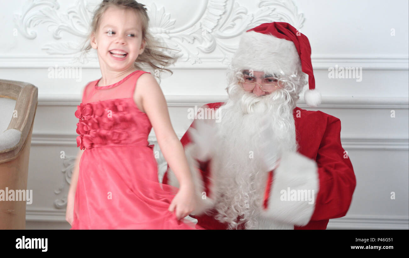 Santa Claus clapping his hands while pretty little girl dancing around ...