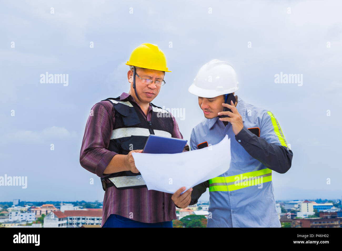 Asian construction engineer working with his foreman while using his ...