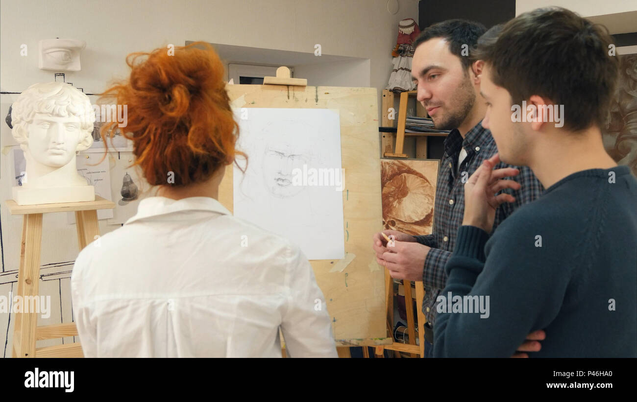 Art teacher explaining two male students how to draw plaster cast Stock ...