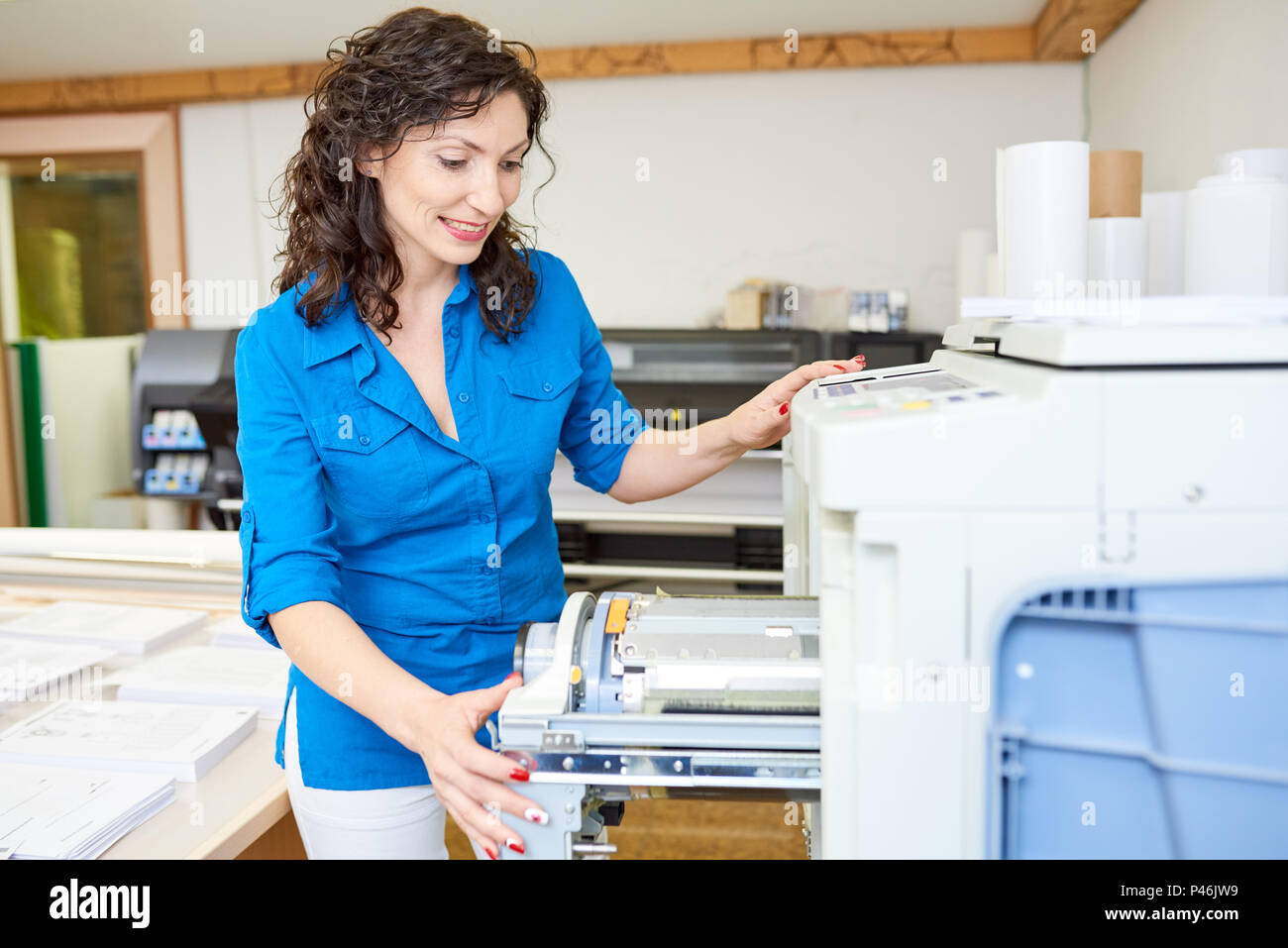 Adult woman checking printer in office Stock Photo - Alamy