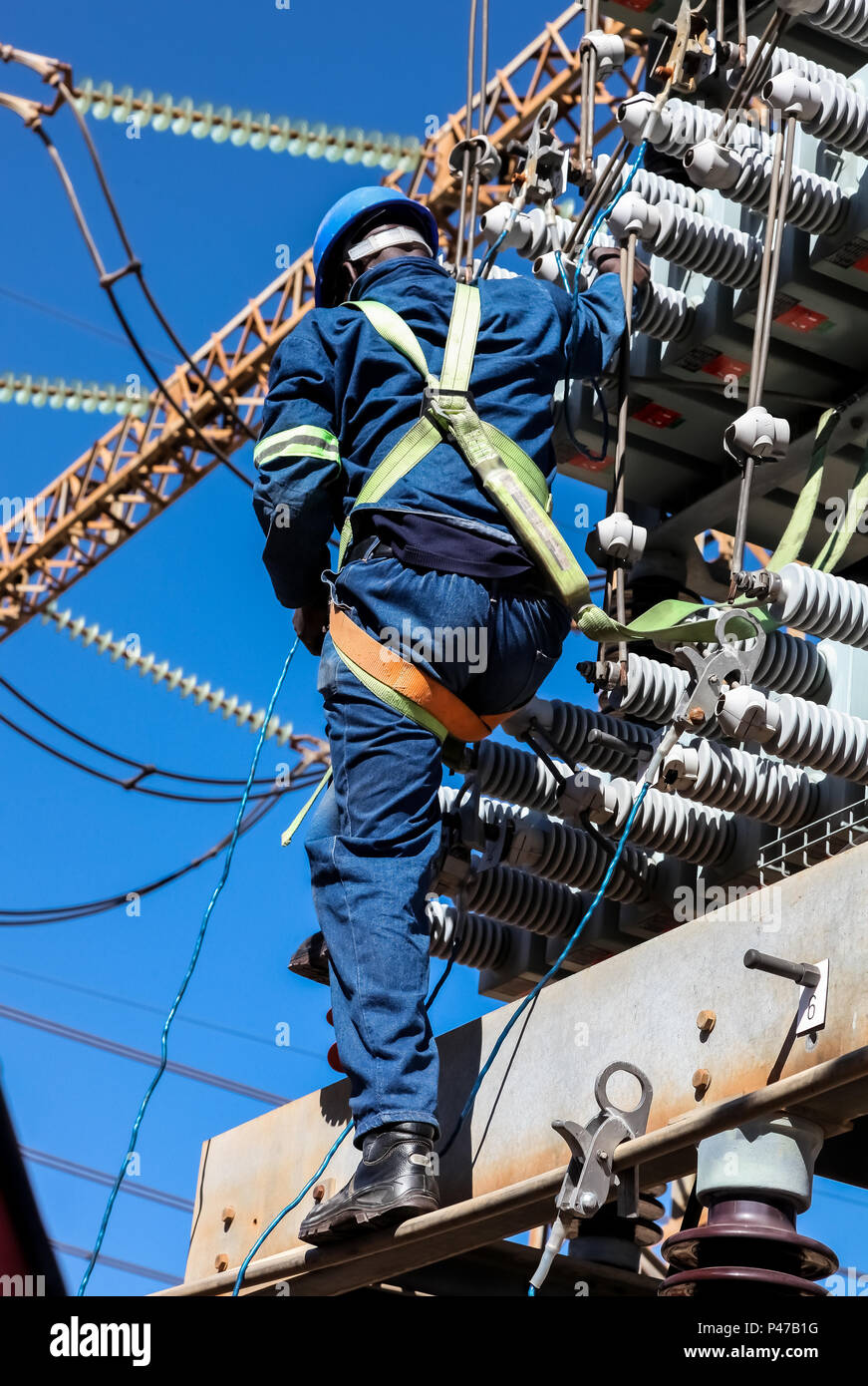 Man working on High Voltage Electric Power Lines at a distribution sub ...
