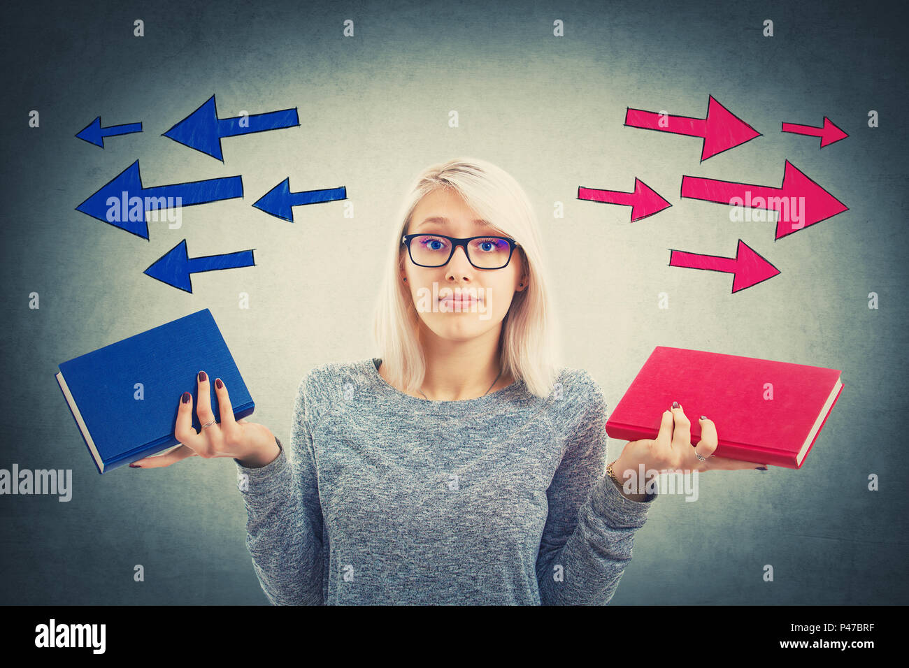 Confused young woman choosing between two books, red and blue, with ...
