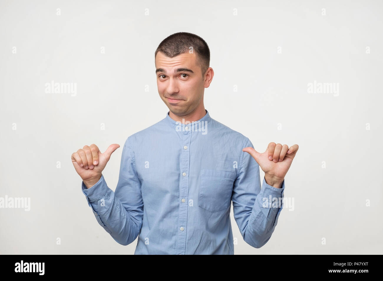 Self-satisfied and proud young man in blue shirt looks forward. He is ...