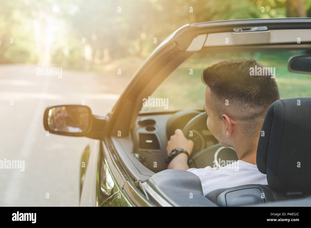 Rear view of driver driving a cabriolet car. On the road travel concept ...