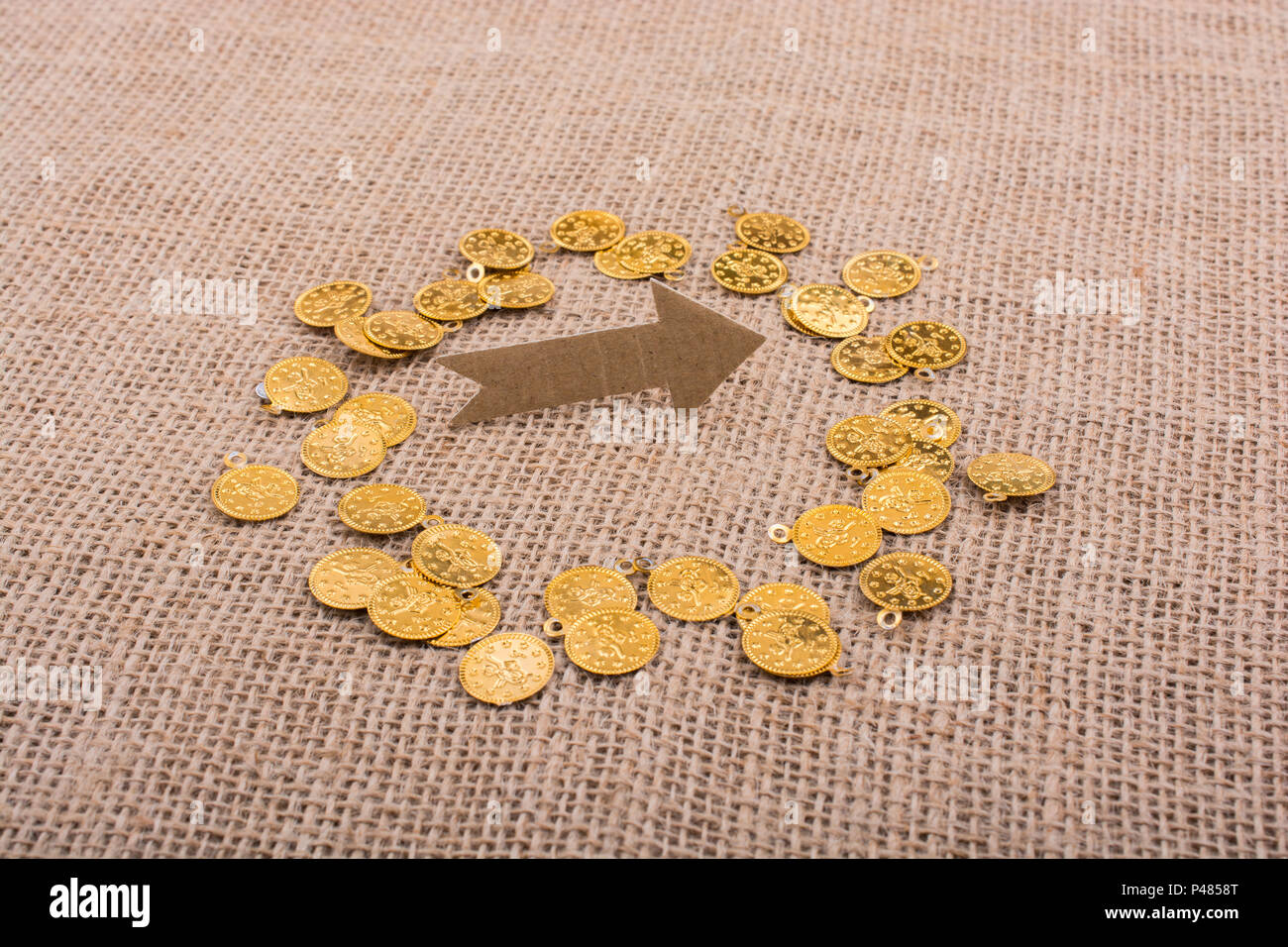 Fake gold coins around arrow shape made of paper Stock Photo - Alamy