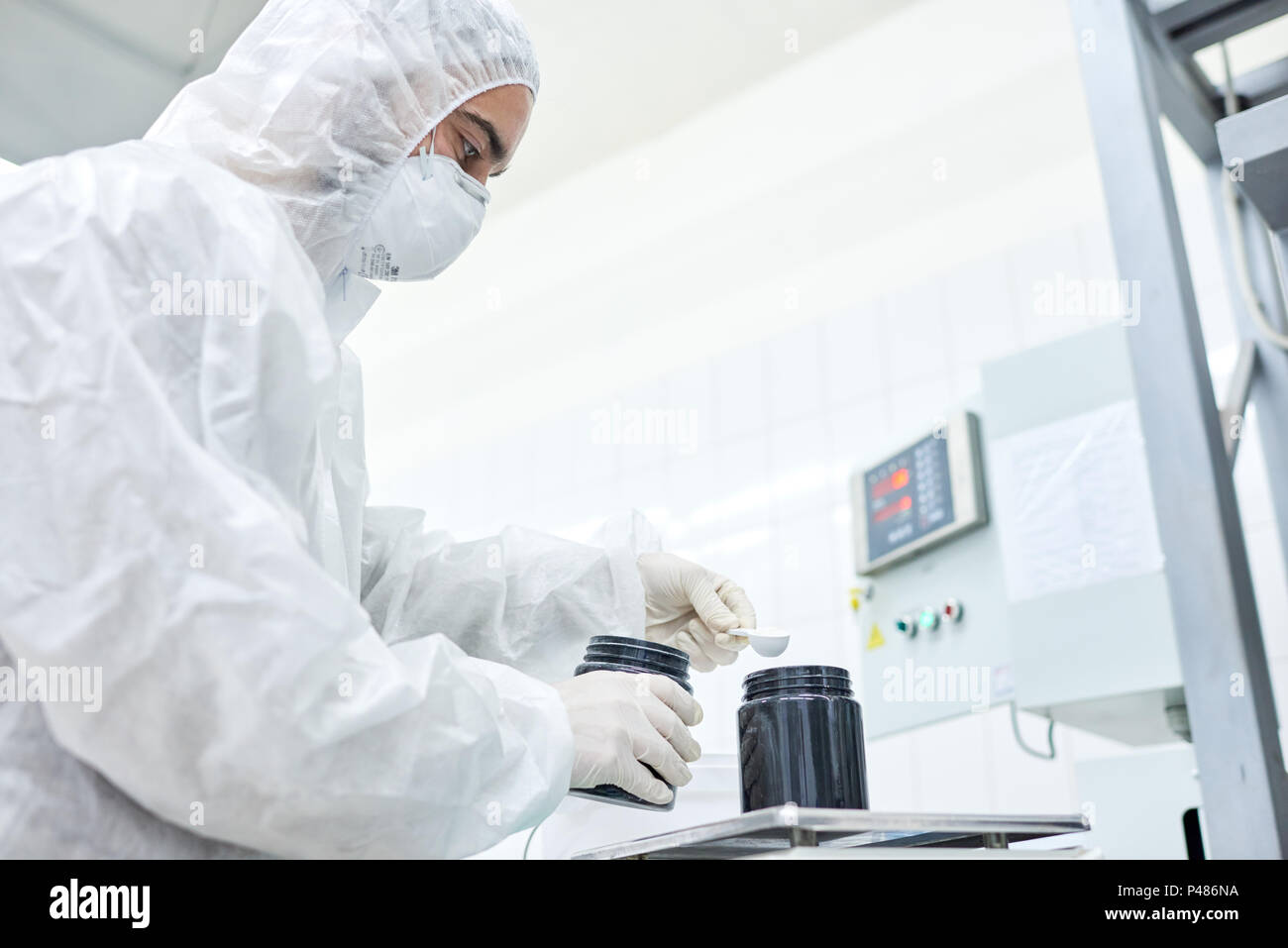 Factory worker adding product to plastic container Stock Photo - Alamy