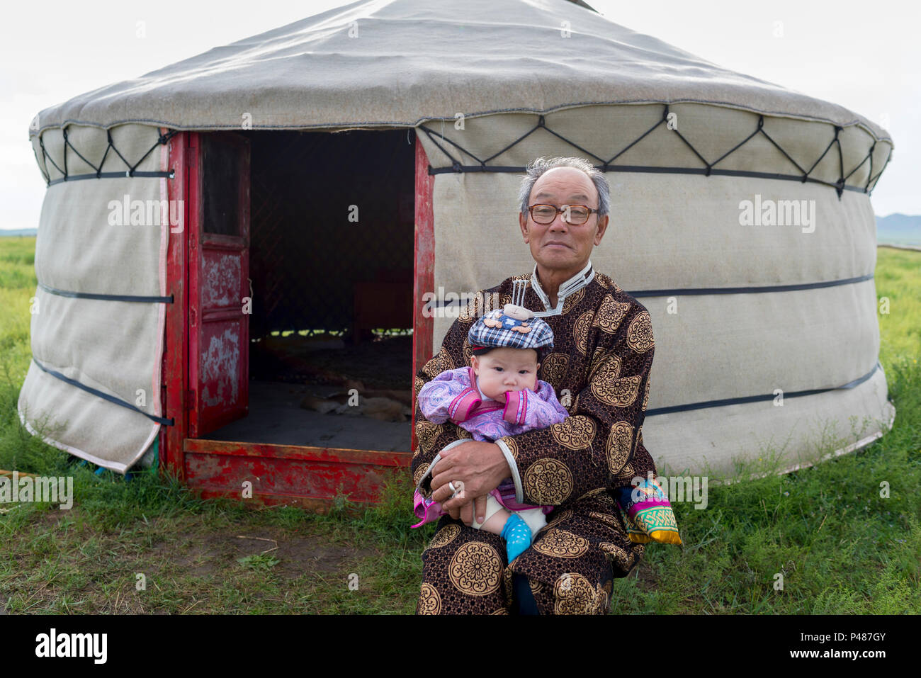 Grandfather with infant grandson outside their summertime yurt ...