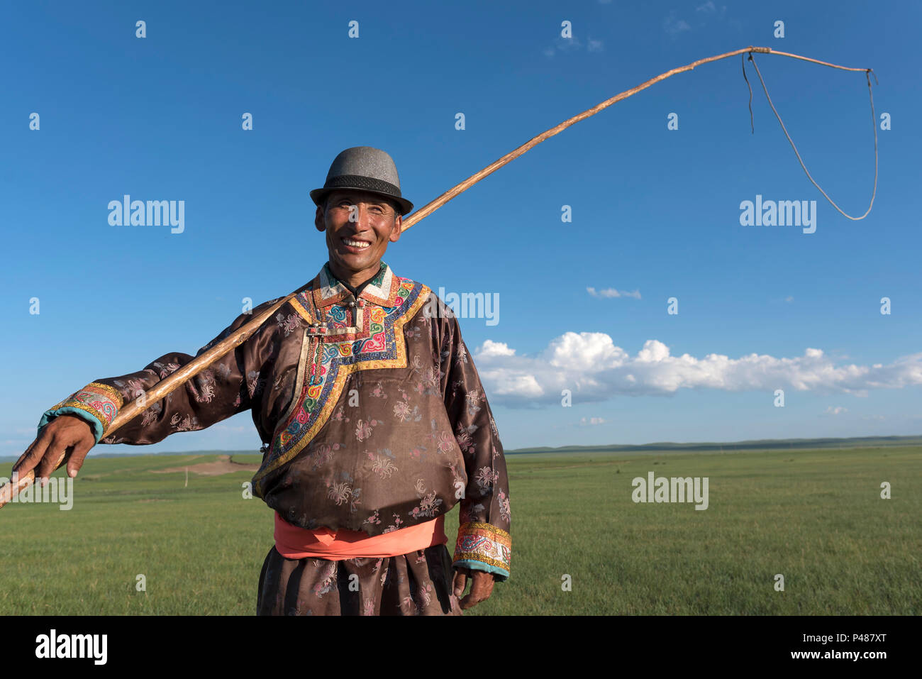 Horseman dressed in traditional costume holds rope and pole urga or ...