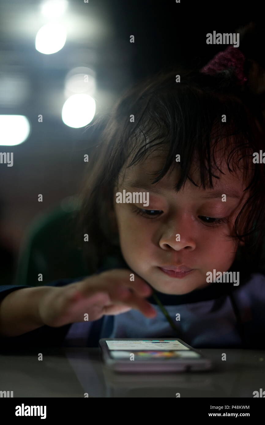 Little Girl Watching movies on a Smartphone at coffee shop Stock Photo ...