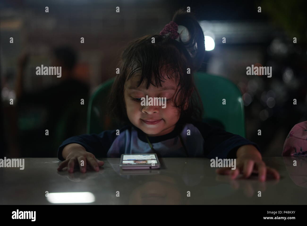 Little Girl Watching movies on a Smartphone at coffee shop Stock Photo ...
