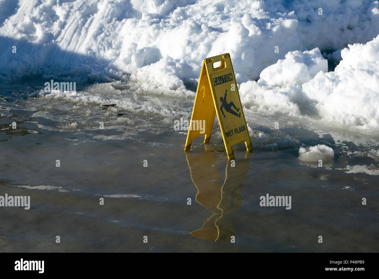 Warning sign for a slippery or icy road surface in front of a melting ...