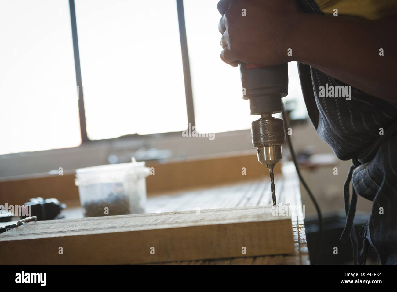 Carpenter drilling wooden plank with machine Stock Photo - Alamy