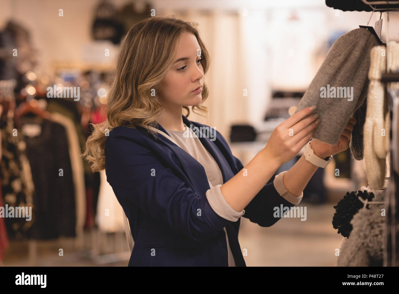 Beautiful woman checking out hat in display Stock Photo - Alamy