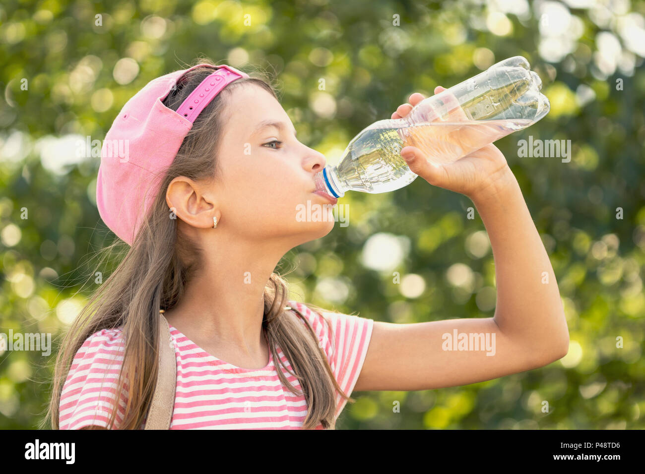 Thirsty child girl drinking water in a park Stock Photo - Alamy