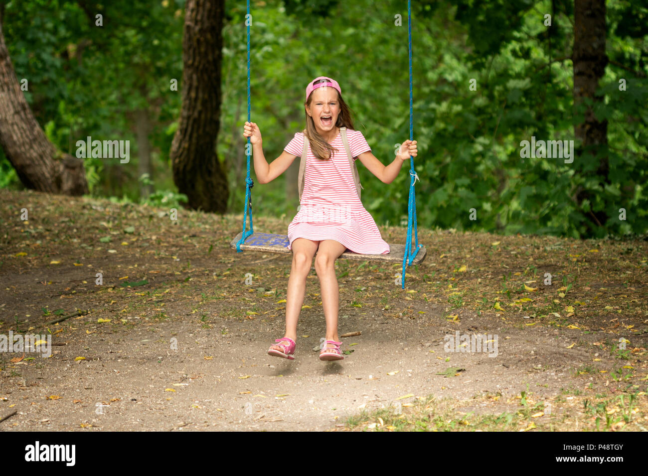 Laughing girl swinging on a tree swings Stock Photo - Alamy