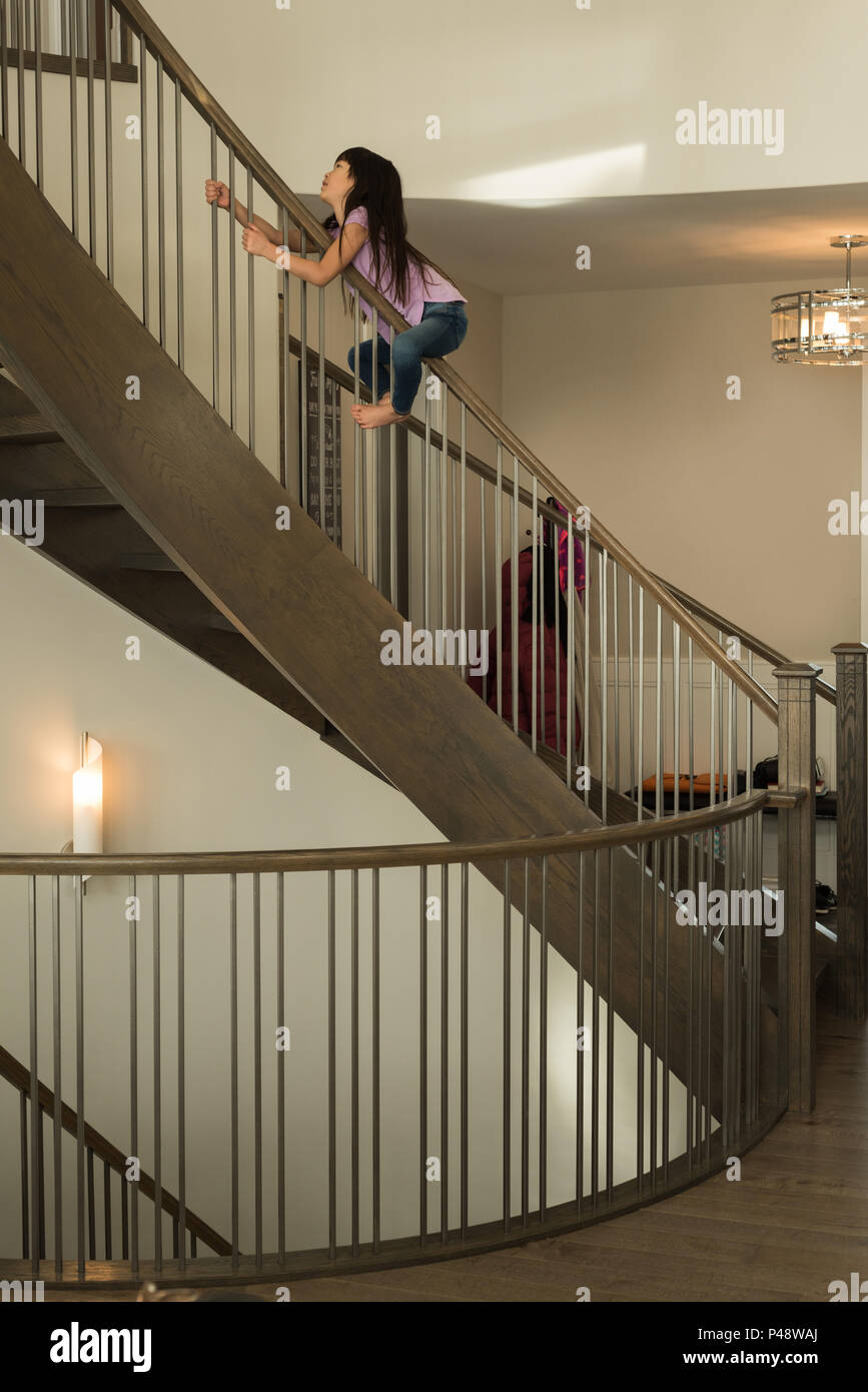 Girl playing on staircase railing at home Stock Photo - Alamy