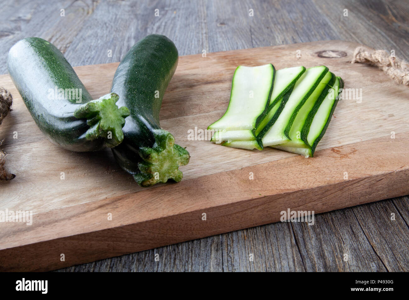 Two Courgettes on a wooden chopping board and another julienne ...