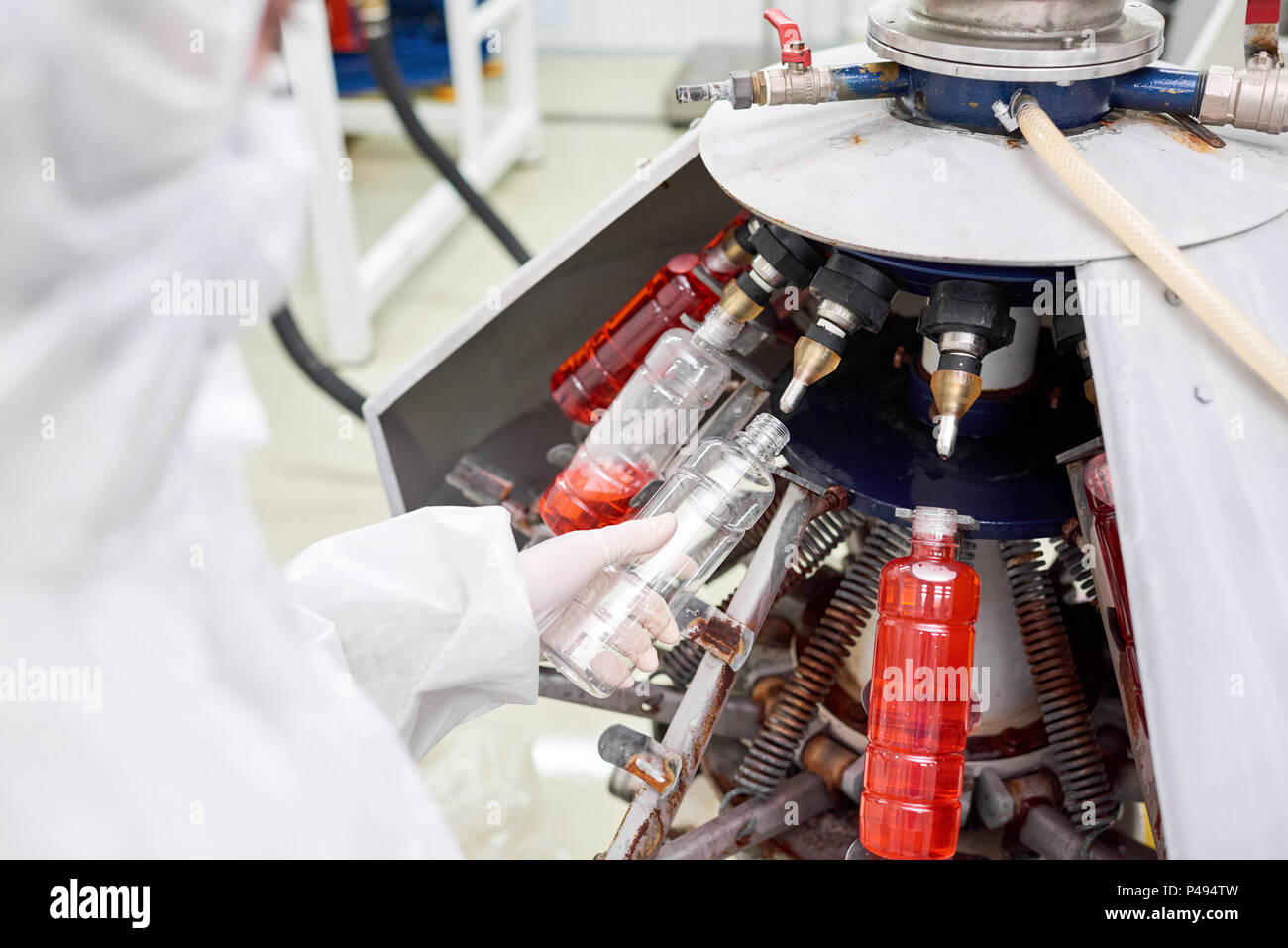 Factory worker placing empty bottle into filling machine Stock Photo ...
