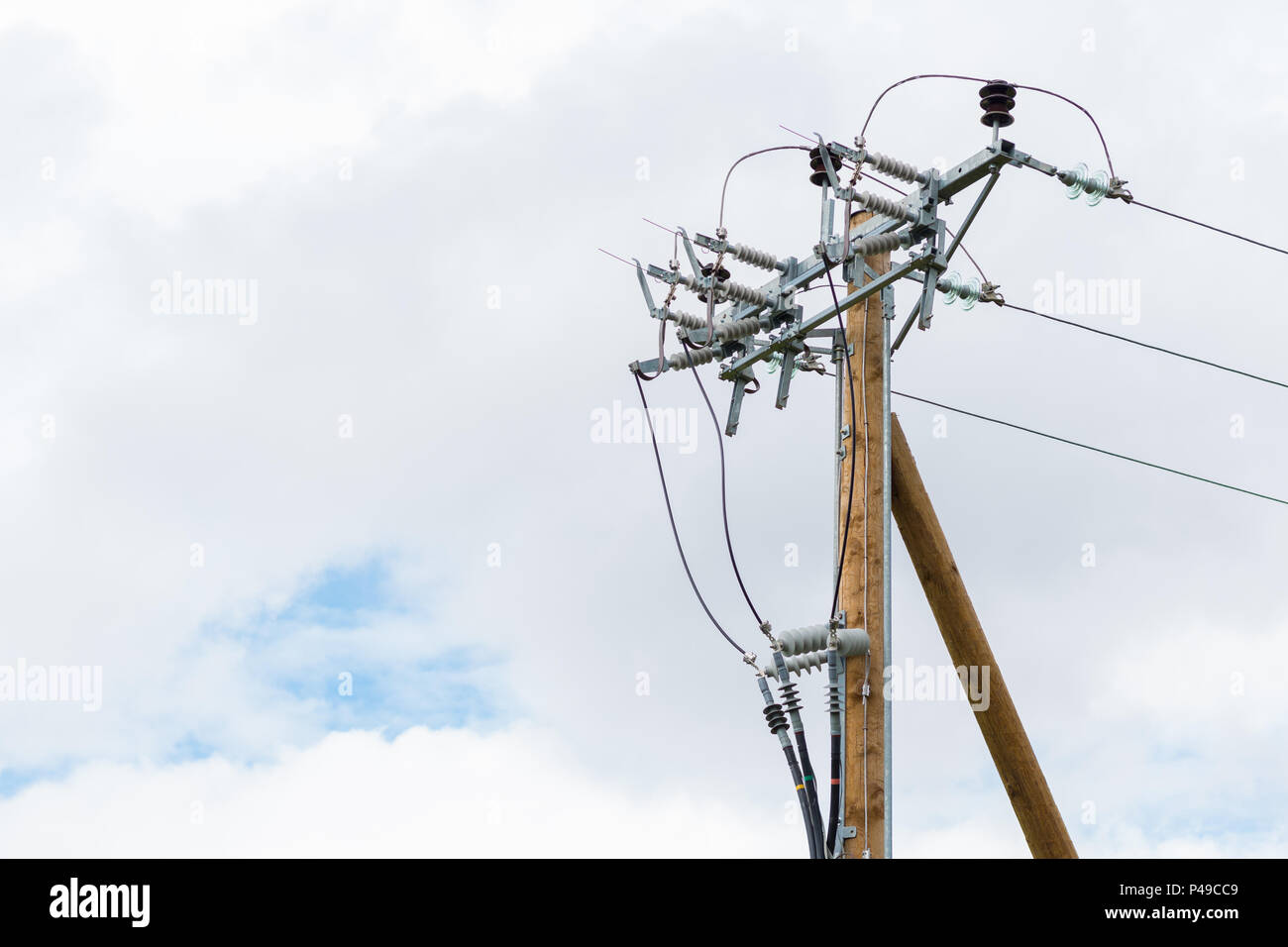 Brand new wooden electricity pole in a gray cloudy day with 3 lines ...