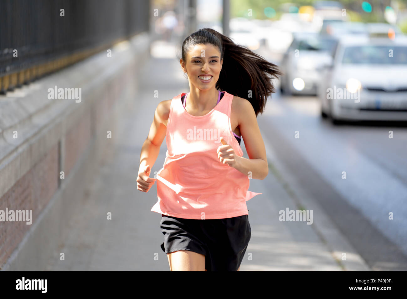 attractive young latin female runner jogging on the city street with ...