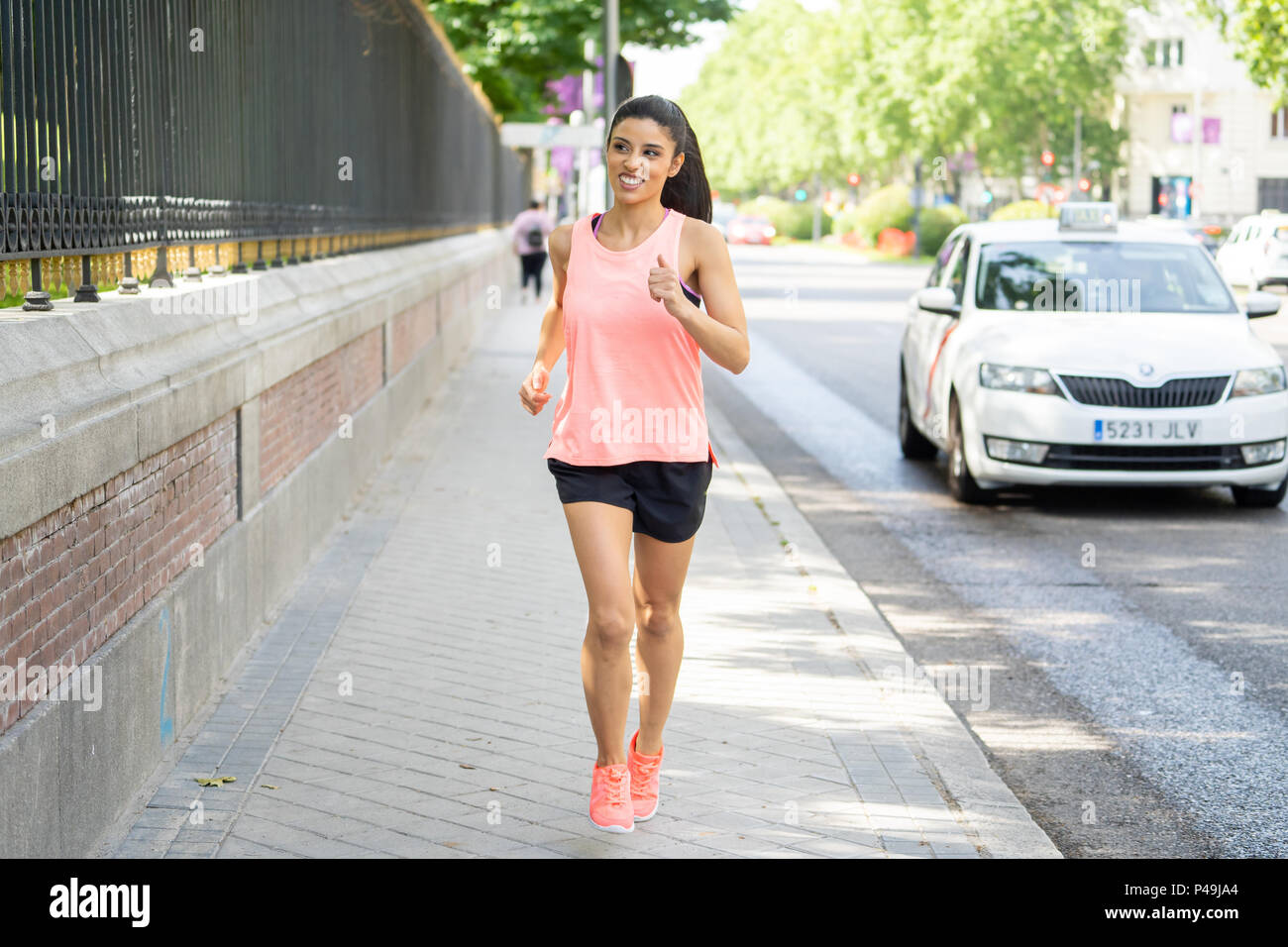 attractive young latin female runner jogging on the city street with ...