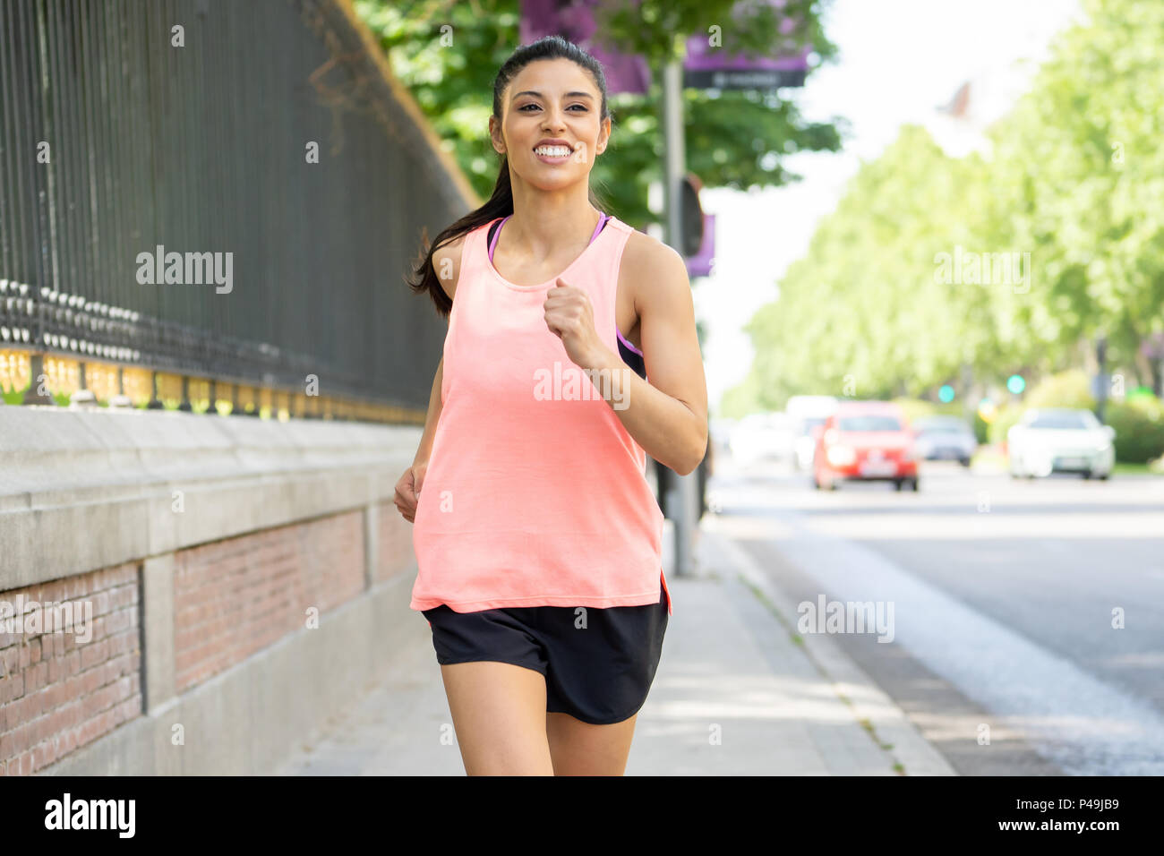 attractive young latin female runner jogging on the city street with ...