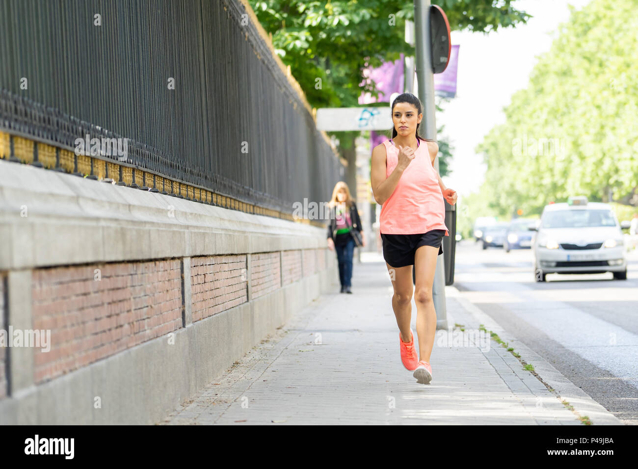 attractive young latin female runner jogging on the city street with ...