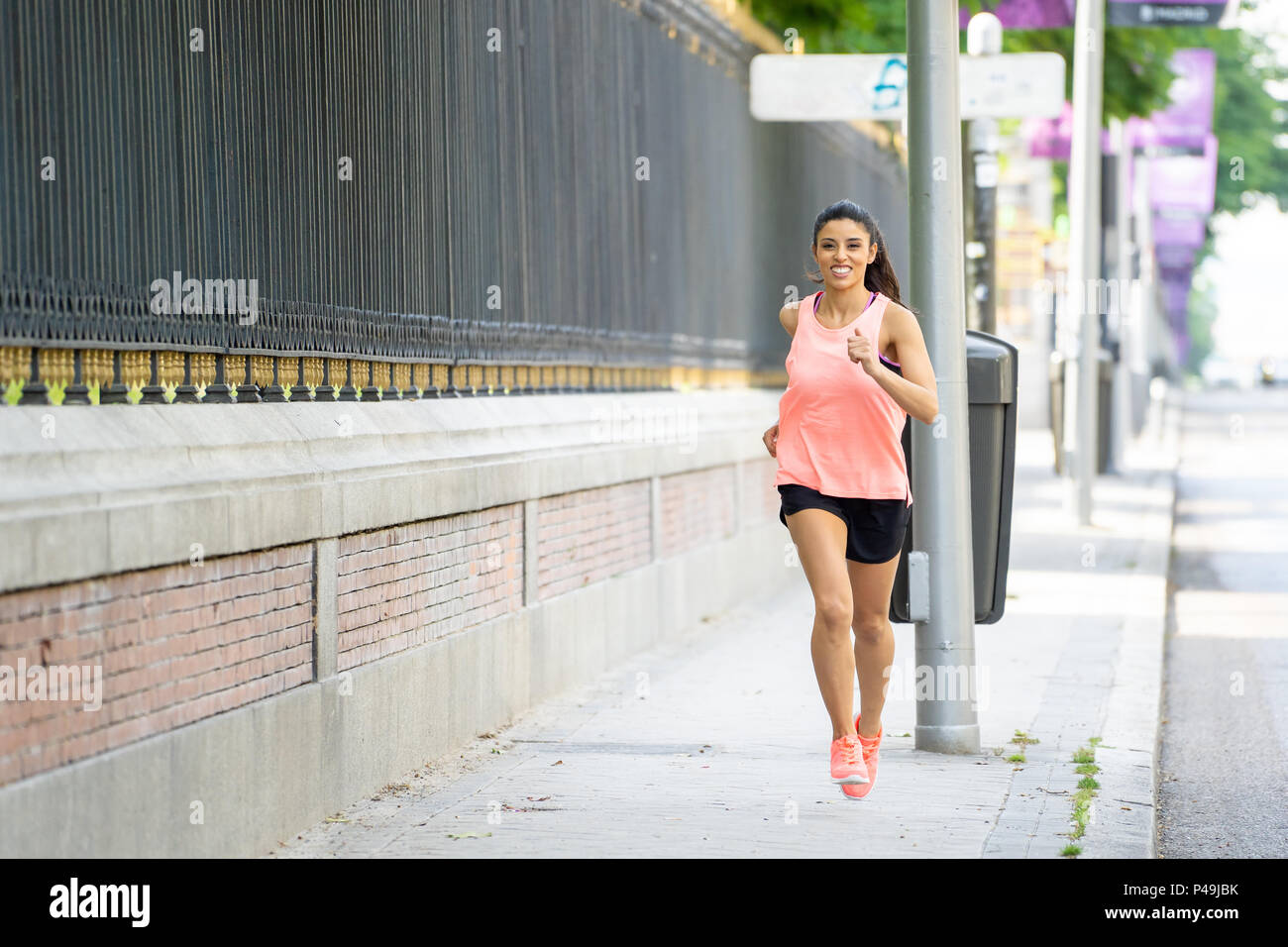 attractive young latin female runner jogging on the city street with ...