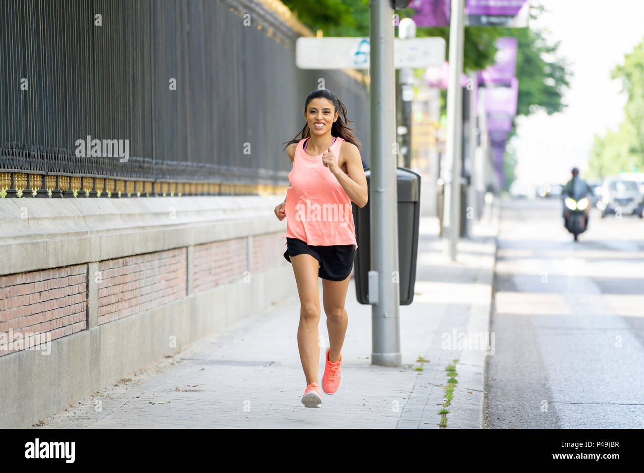 attractive young latin female runner jogging on the city street with ...