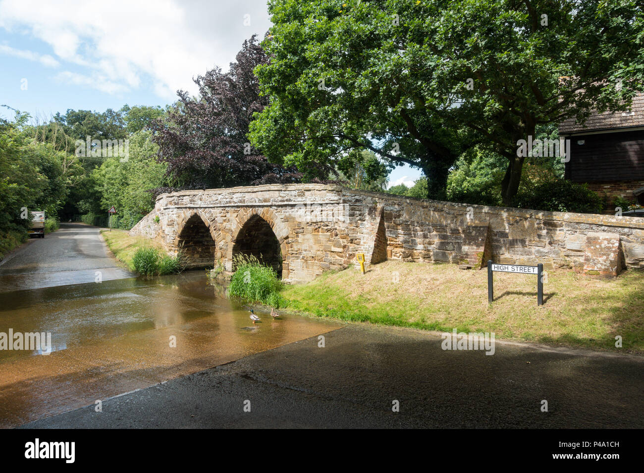 A stone footbridge over a ford in a typical english country village in ...