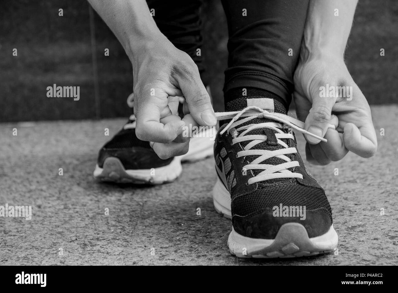 Female runner tying her shoes preparing for a run a jog outside Stock ...