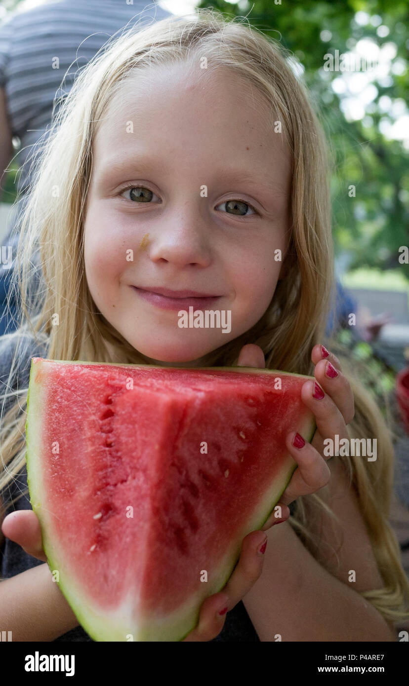 Dreamy girl age 7 ready to bite into a rather large wedge of watermelon ...