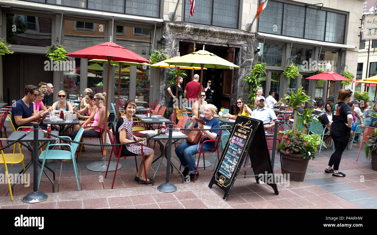 Sidewalk diners under umbrellas at the Local Irish Pub cheerfully watch ...