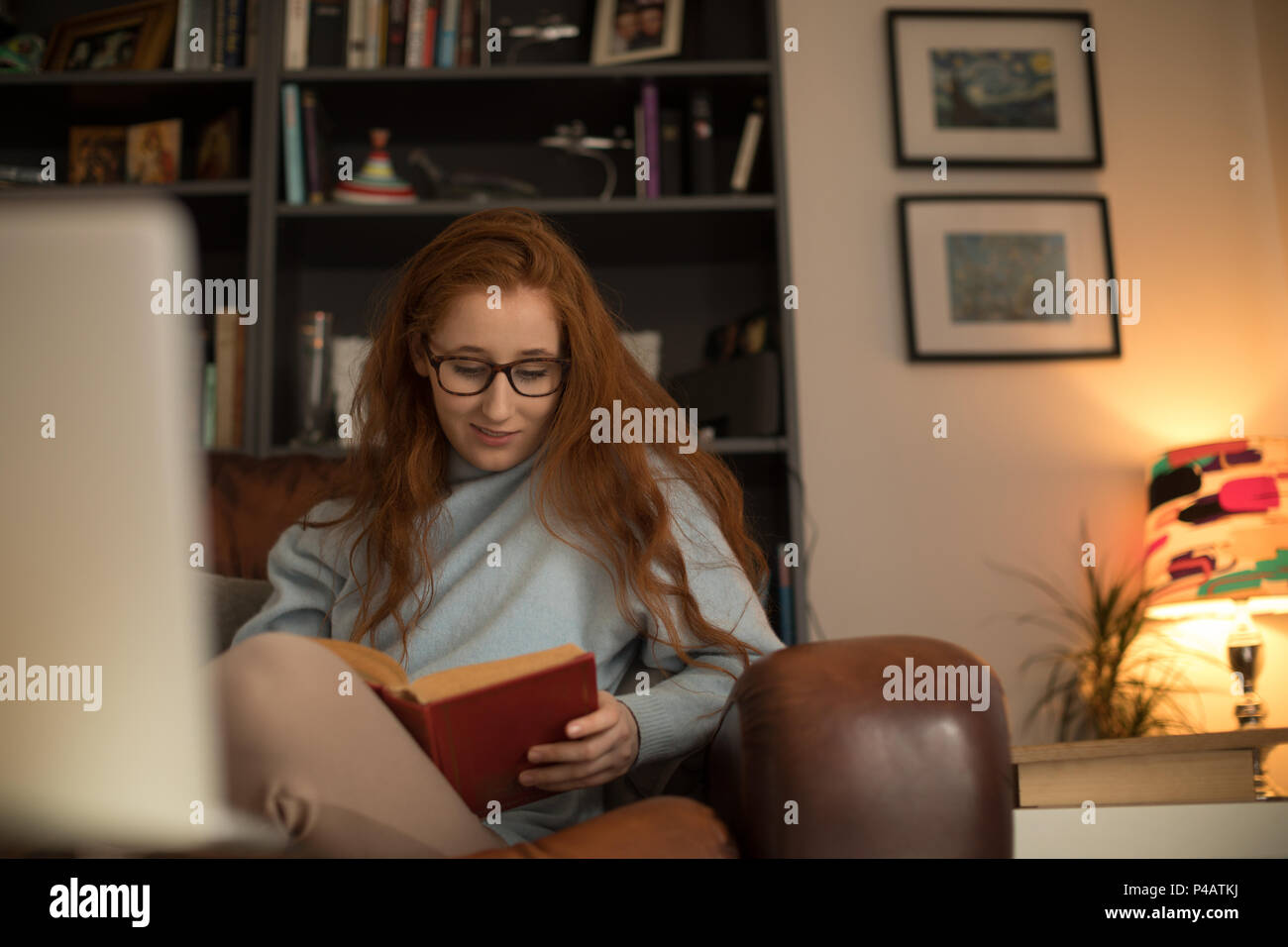 Woman reading a book in living room Stock Photo - Alamy