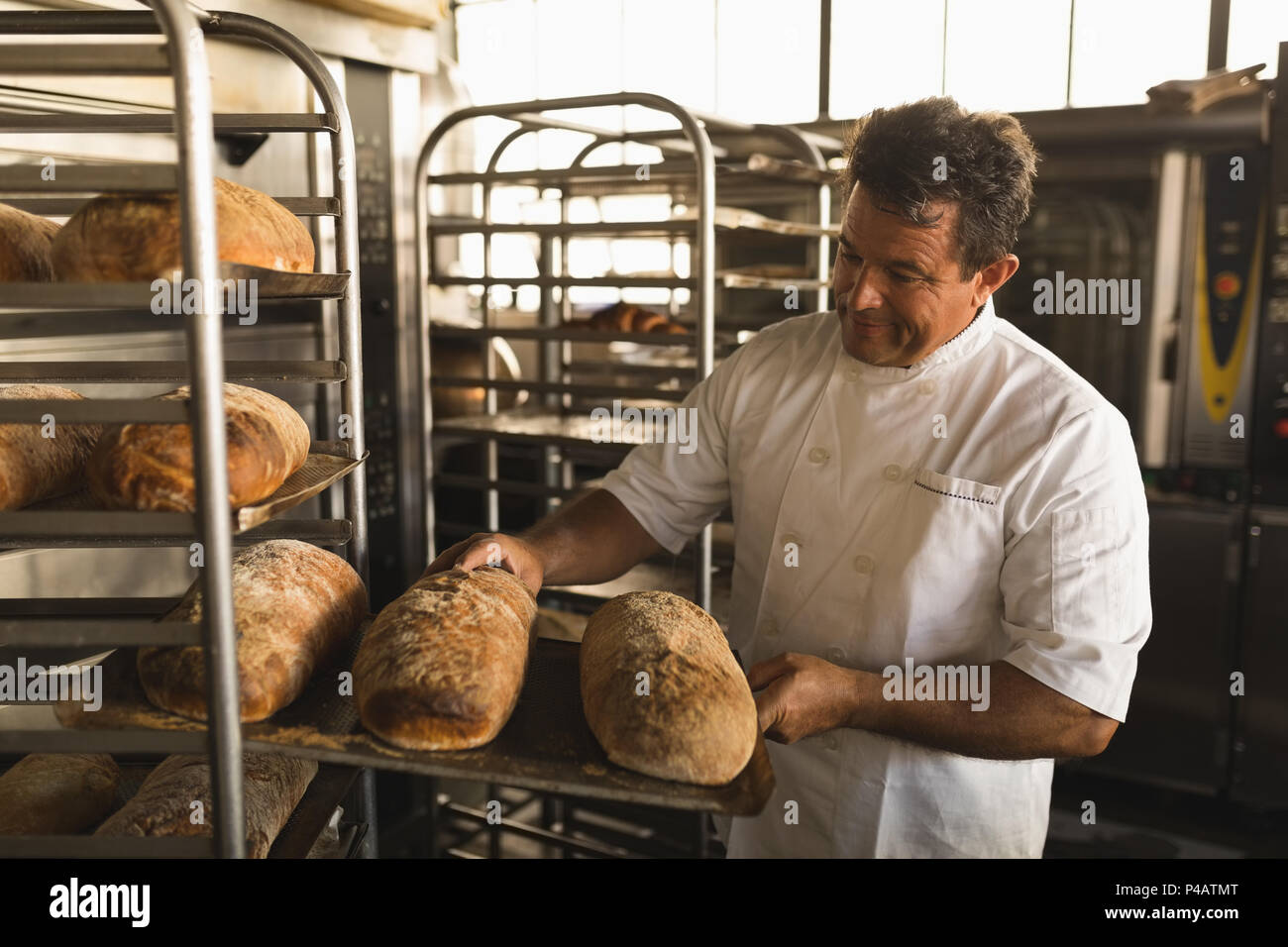 Male baker checking baked bread Stock Photo - Alamy