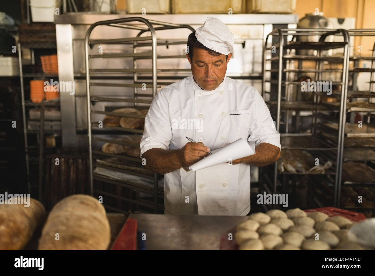 Male baker writing on a notepad Stock Photo - Alamy