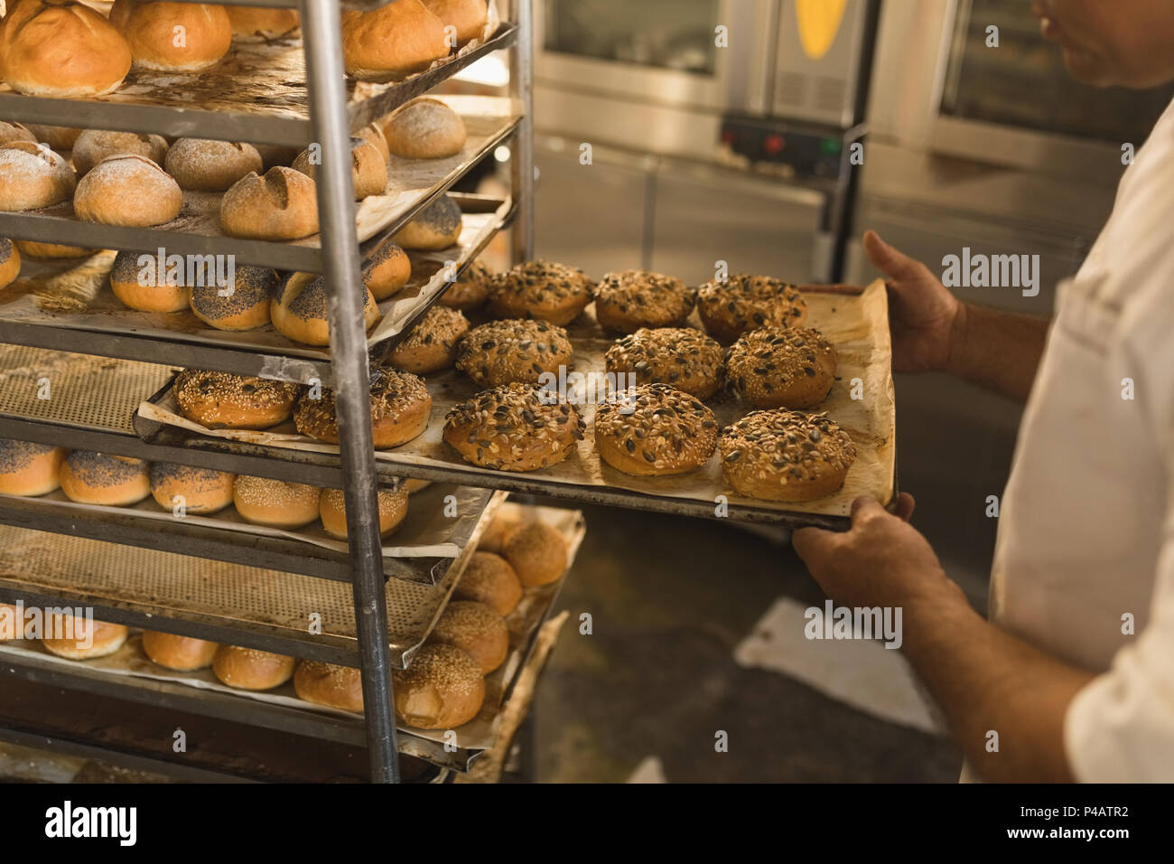 Male baker removing a tray of sweet foods Stock Photo - Alamy