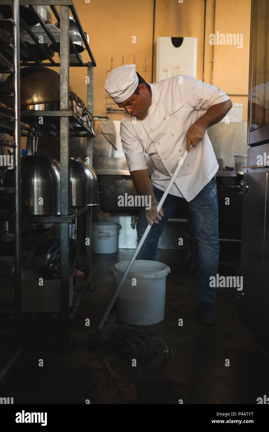 Male baker cleaning floor with floor mop Stock Photo - Alamy