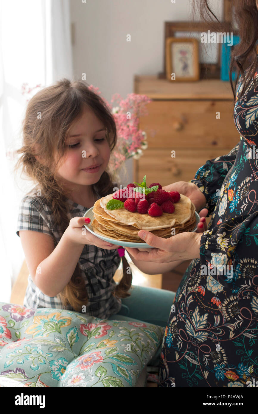 Mom and the girl are holding a plate with homemade pancakes and berries ...
