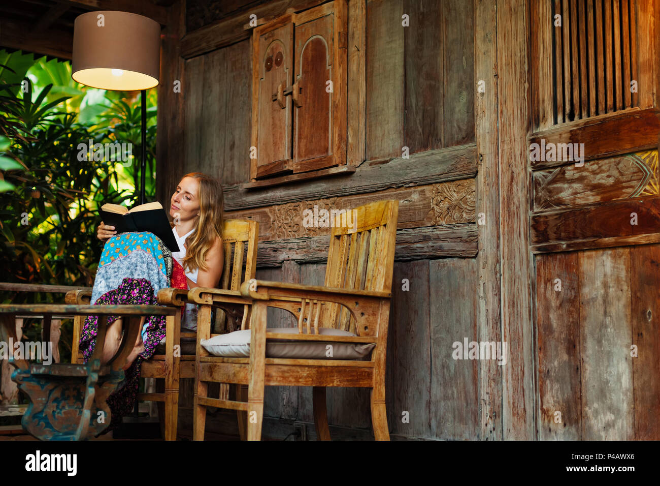 Attractive girl sit on open-air veranda of wooden bungalow with ...