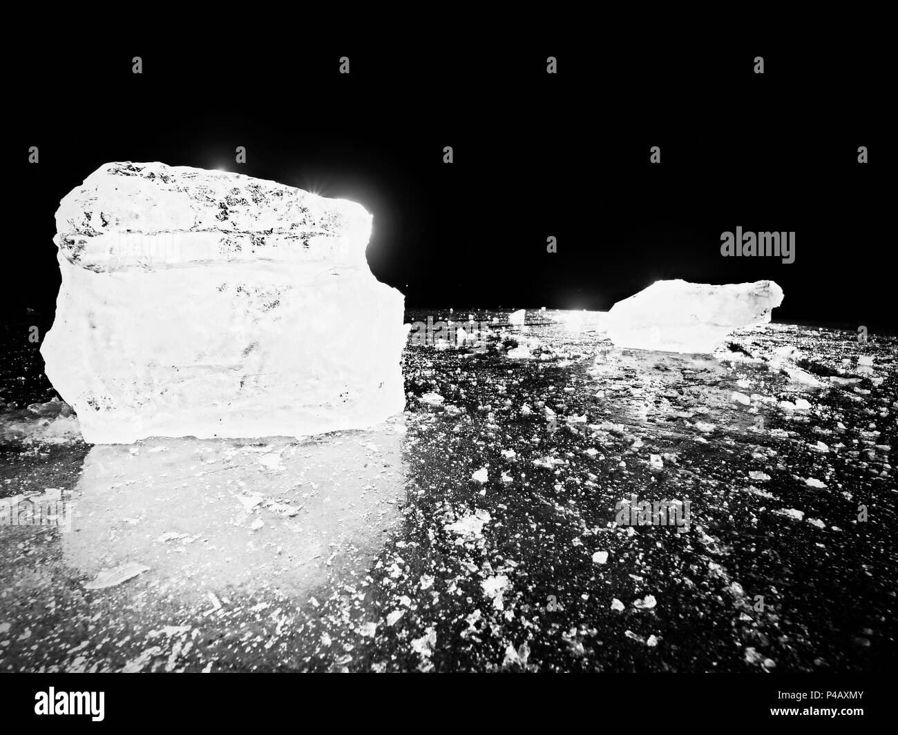 Ice cubes on a dark reflective ground. Glowing pieces of chopped ice ...