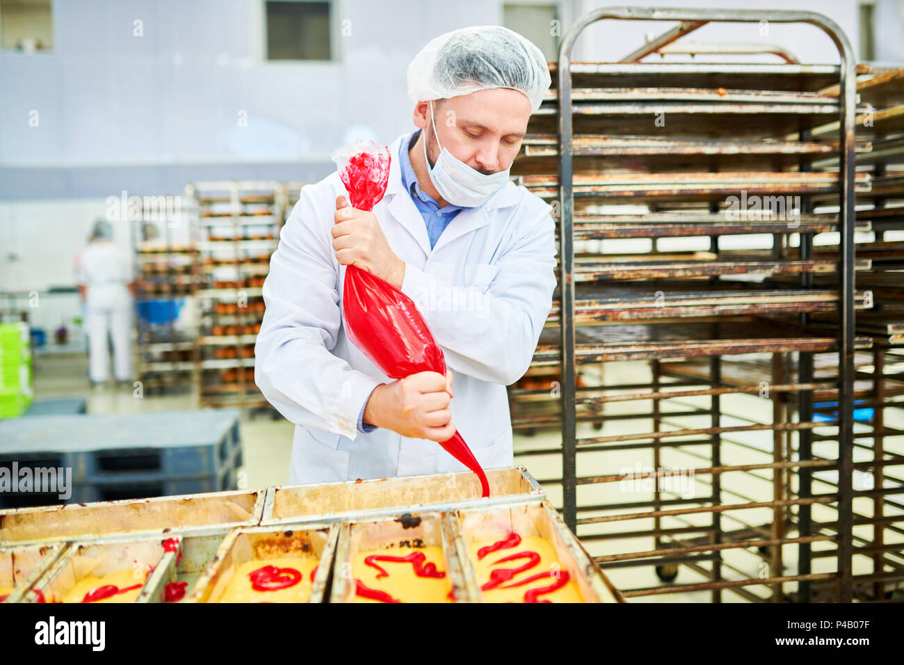 Confectionery factory employee using icing bag Stock Photo - Alamy