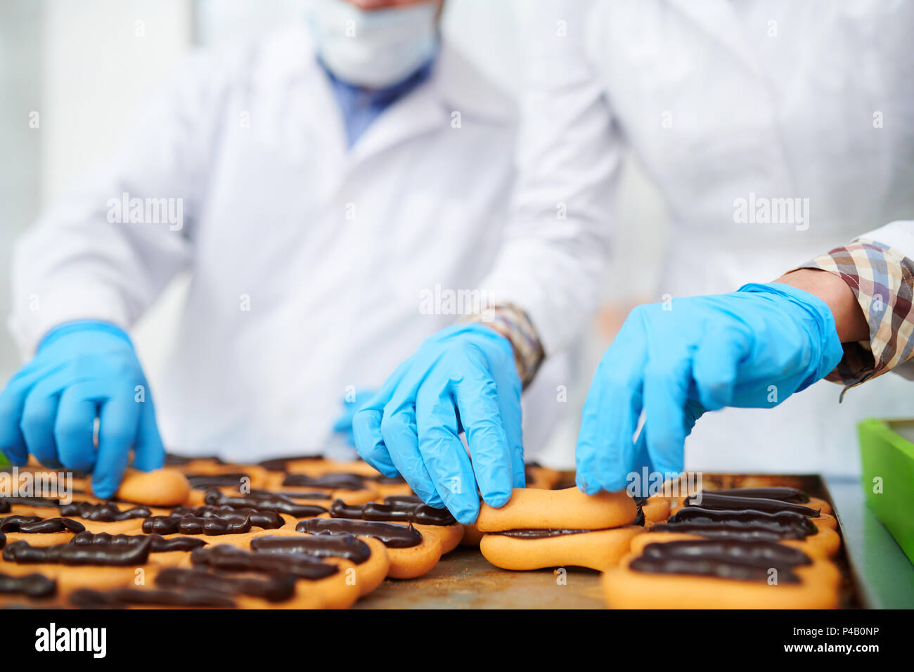 Confectionery factory employees making pastry with chocolate filling ...