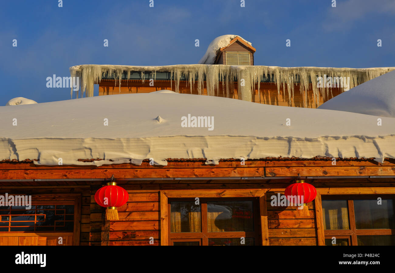 A traditional wooden house covered by snow at the village in Harbin ...